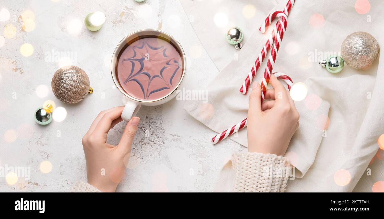 Female hands with cup of melted chocolate and candy canes on white ...