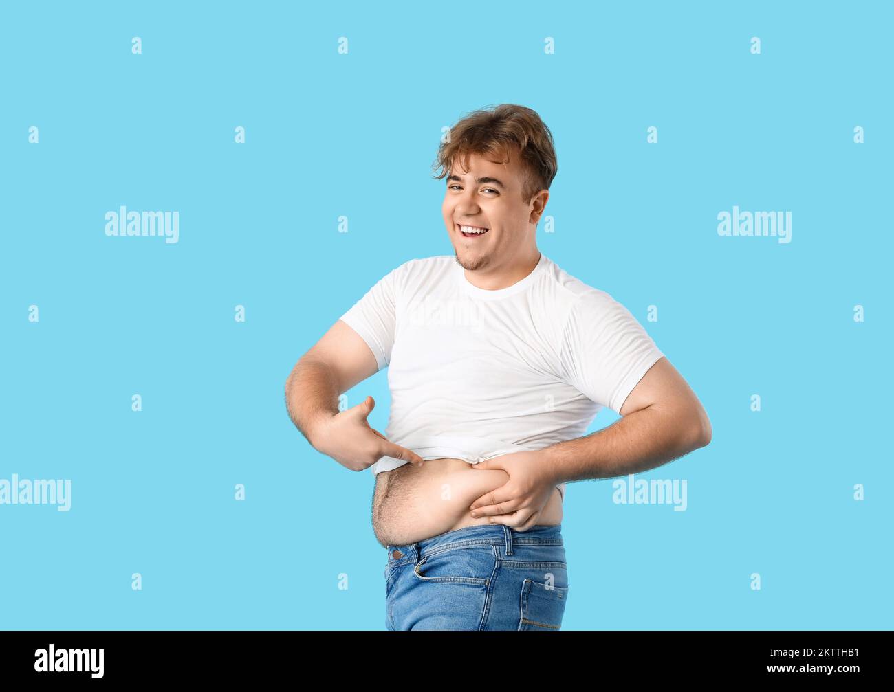 Young overweight man pointing at his belly on blue background Stock ...