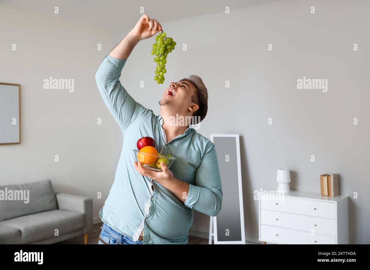 Young overweight man with bowl of fruits at home Stock Photo - Alamy