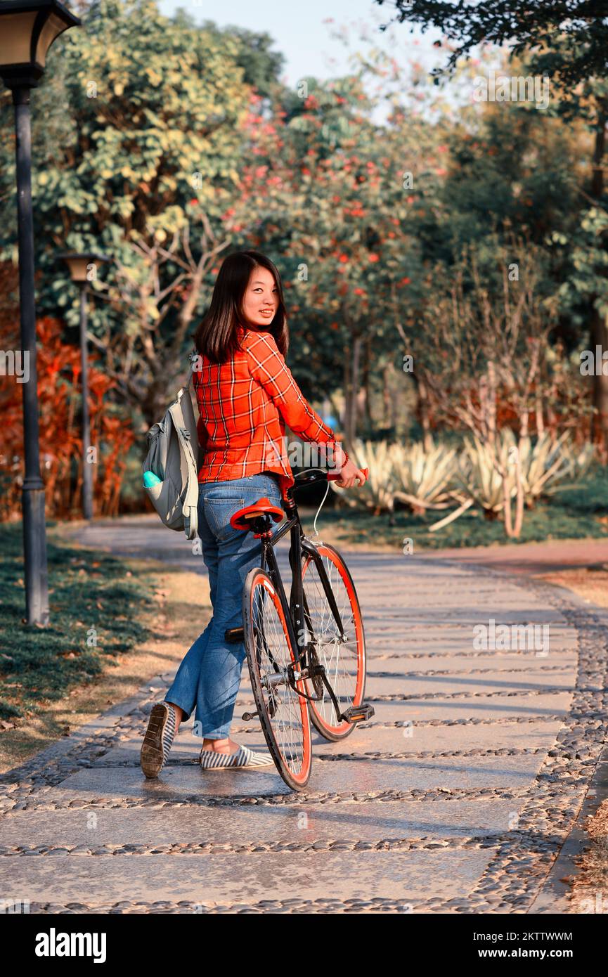 Pretty young chinese woman in the park walking with bicycle Stock Photo ...