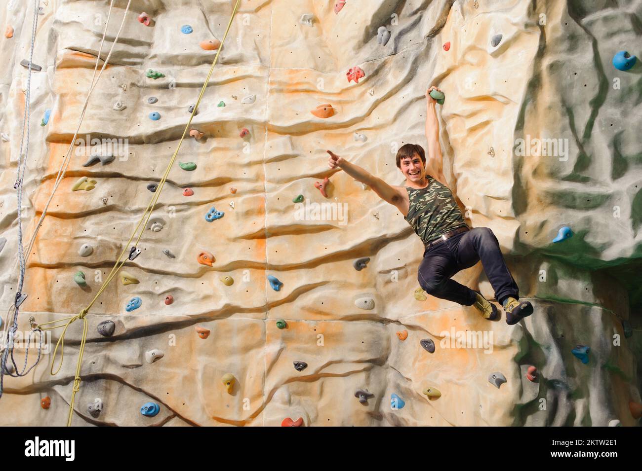 Man climbing on man-made cliff in the sport centre Stock Photo - Alamy