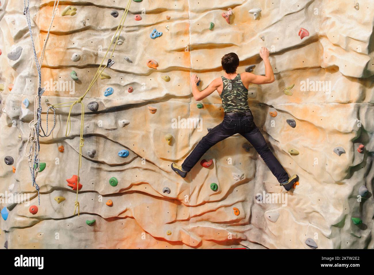 Man climbing on man-made cliff in the sport centre Stock Photo - Alamy