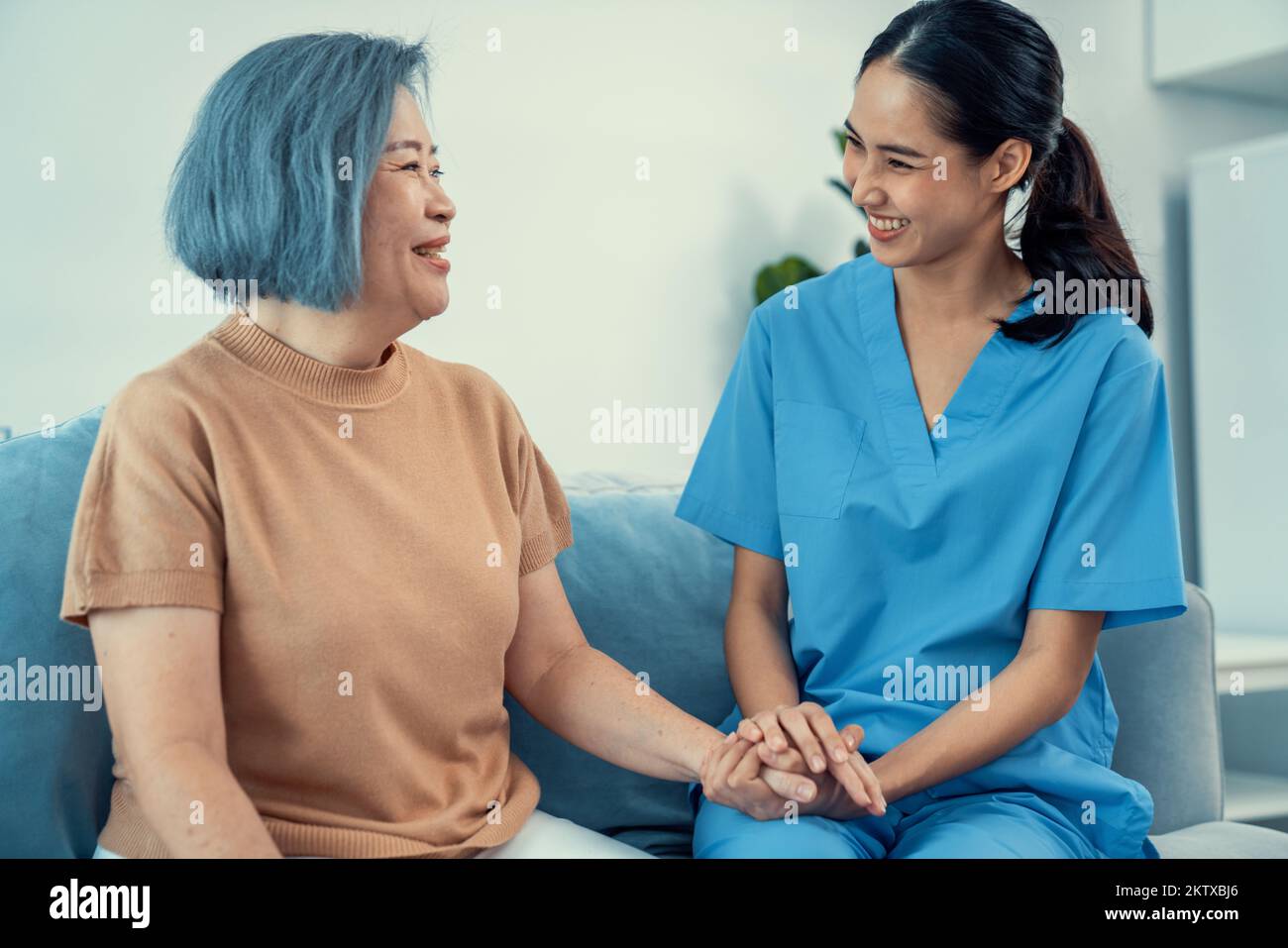 A caregiver rest her hands on the shoulders of a contented senior ...