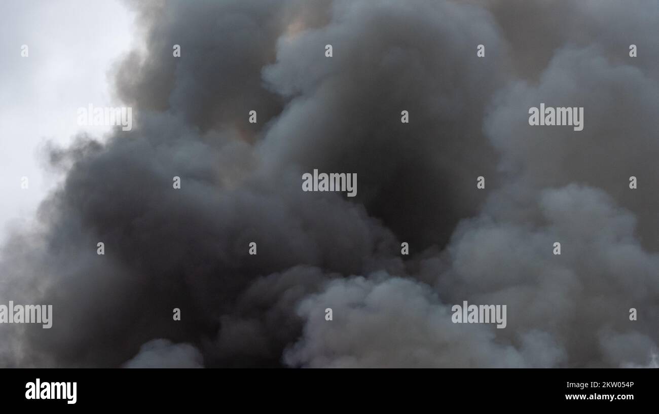 A cloud of black smoke from a fire in a building materials warehouse ...