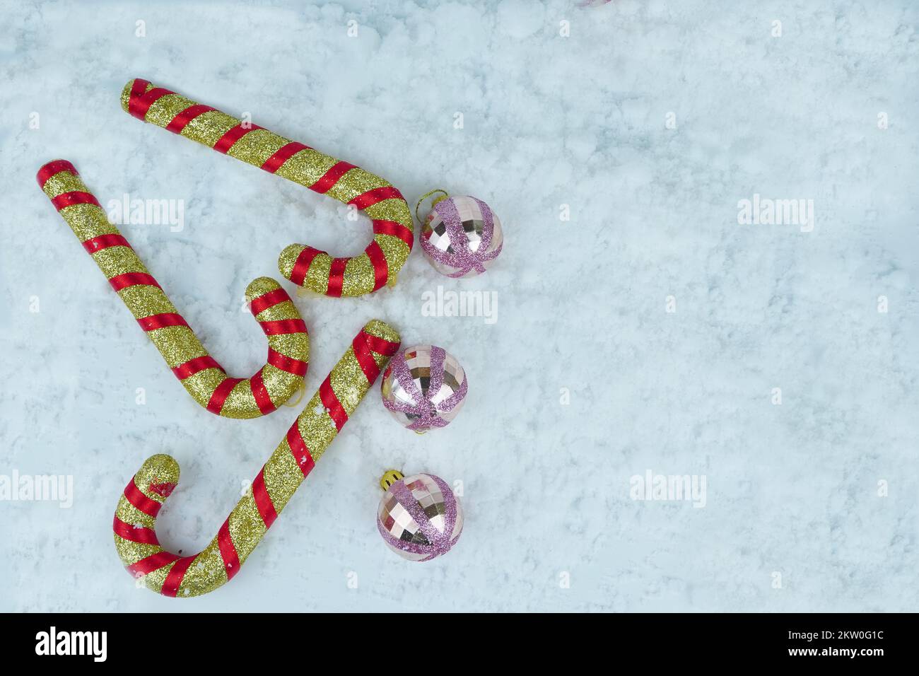 Gold and red candy canes with glitter Christmas baubles on the snow ...