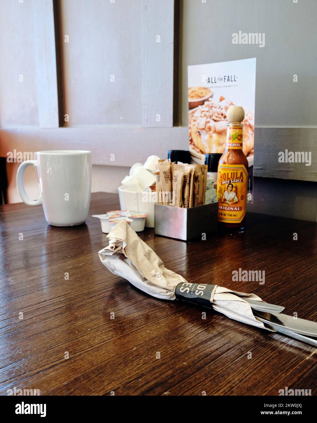 Restaurant table breakfast set up with wrapped utensils, coffee cup and ...