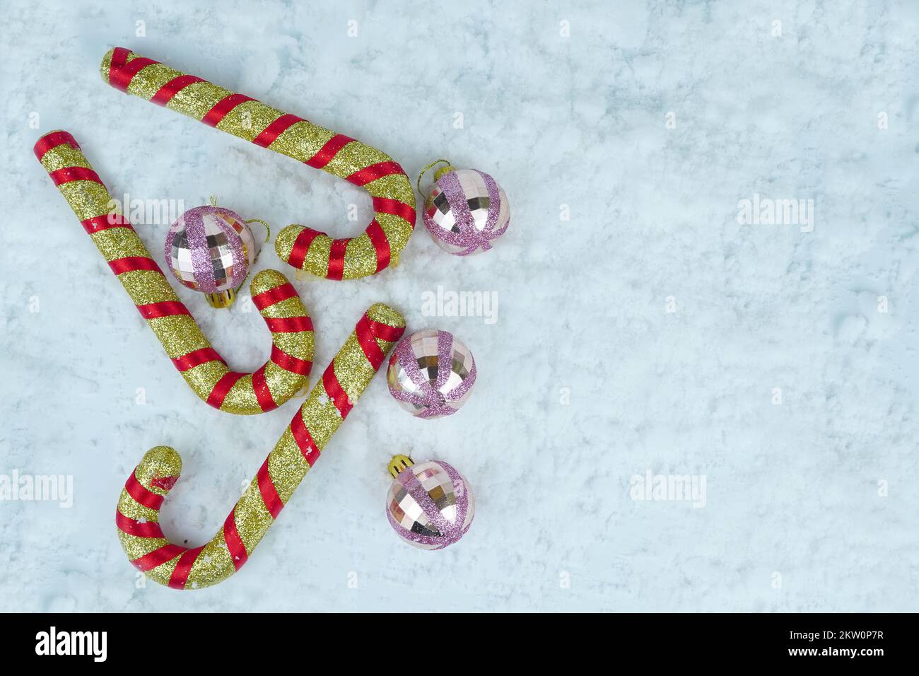 Gold and red candy canes with glitter Christmas baubles on the snow ...
