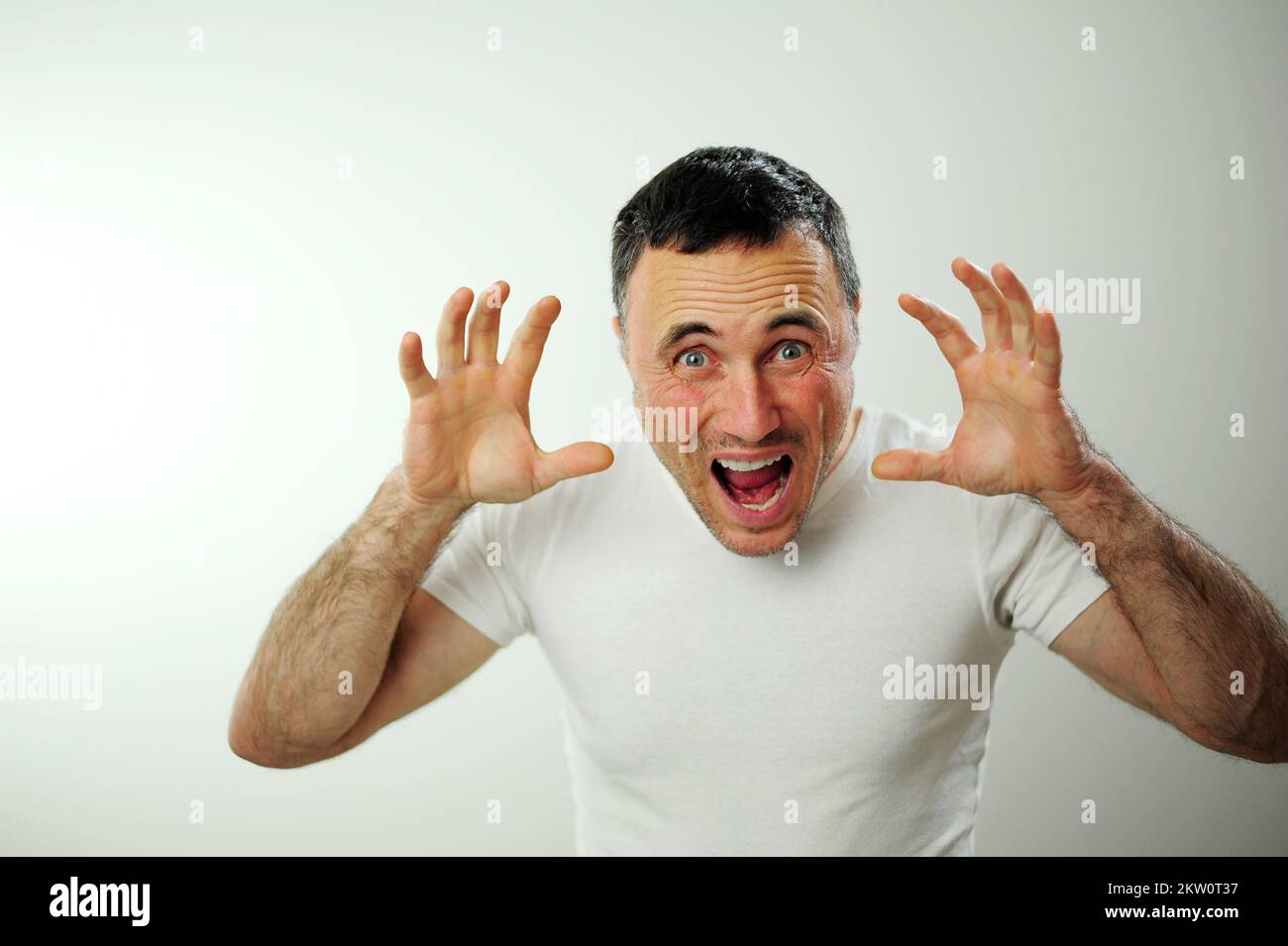 A middle-aged man with kind eyes as if trying to scare someone spread ...