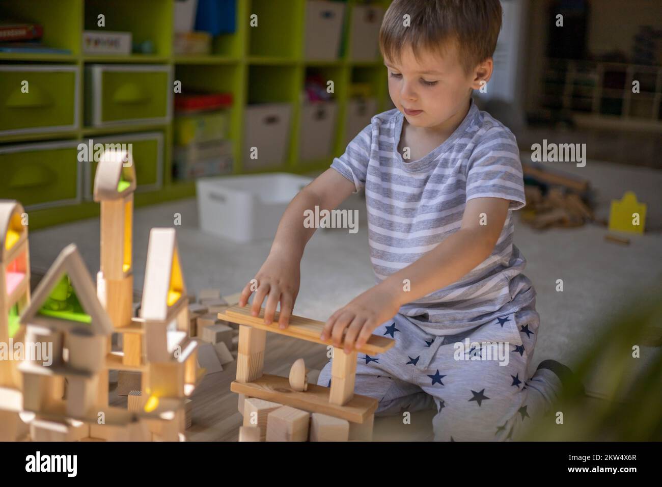 Confident male kid building fortress tower architecture wooden bricks ...