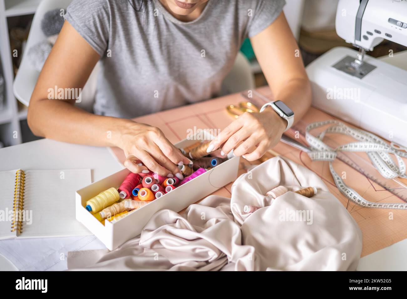 Woman dressmaker hands choosing thread color sewing beige fabric ...