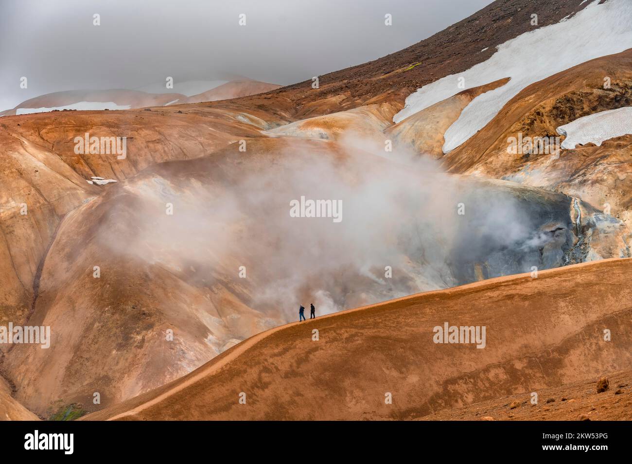 Hikers on a colourful rhyolite mountain, steaming hot springs in the ...