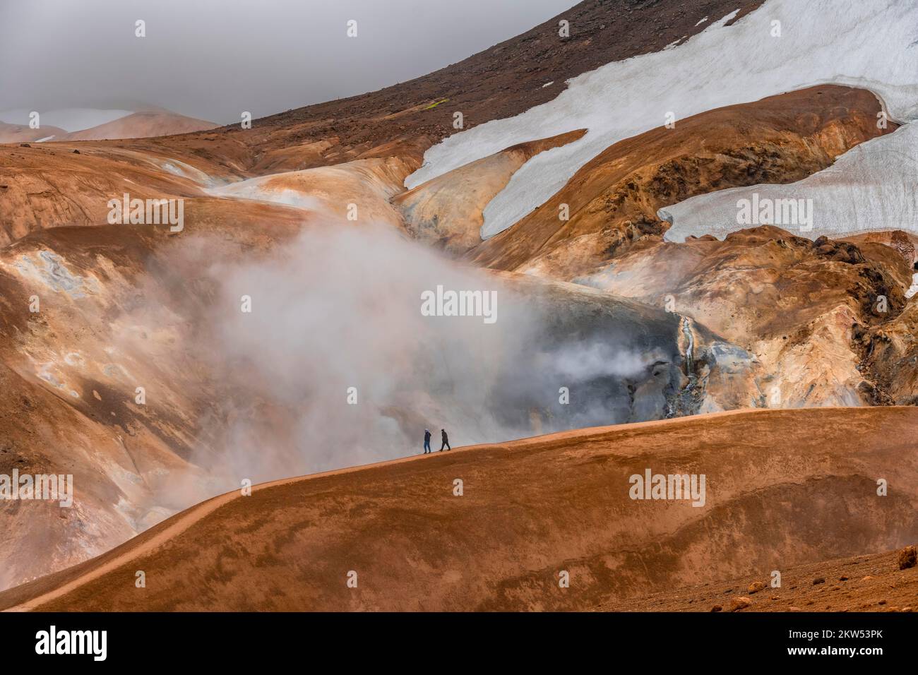 Hikers on a colourful rhyolite mountain, steaming hot springs in the ...