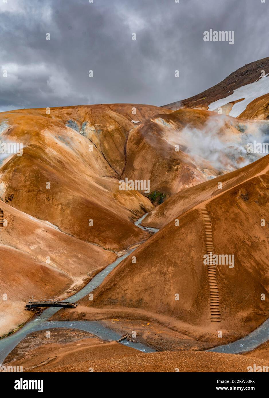 Bridge over steaming stream between colourful rhyolite mountains with ...