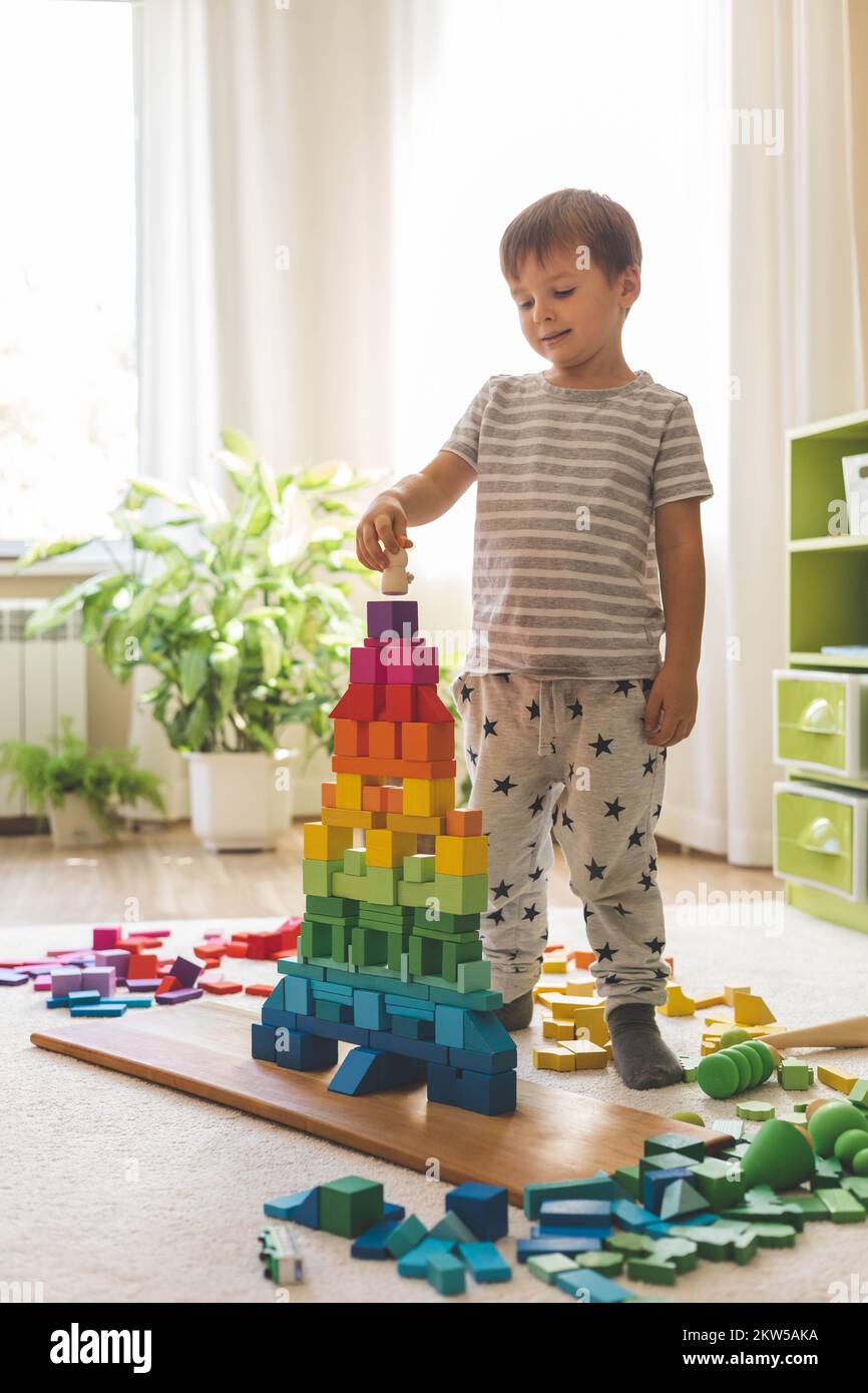 Confident male kid building fortress tower architecture wooden bricks ...
