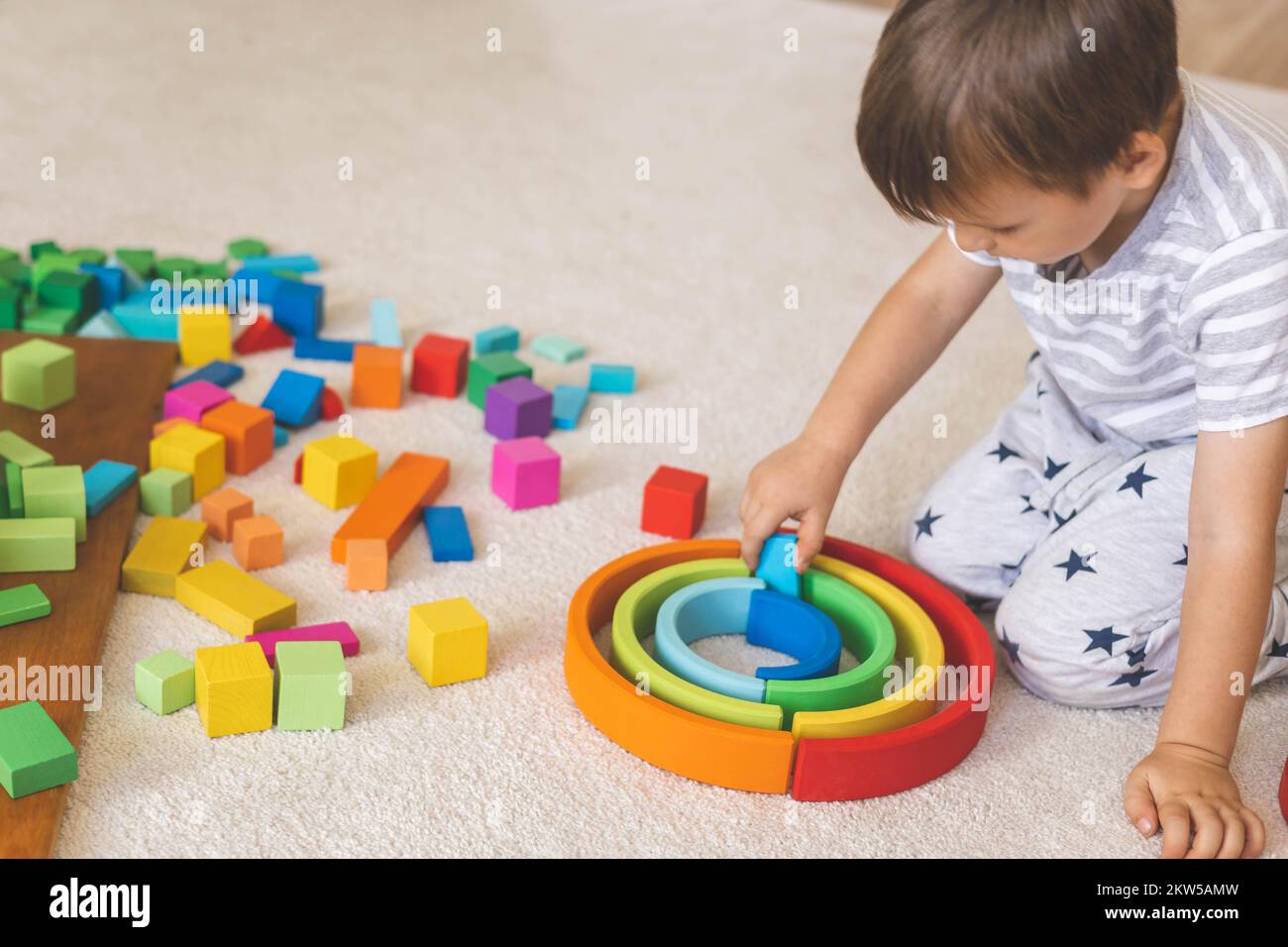 Confident male kid building fortress tower architecture wooden bricks ...