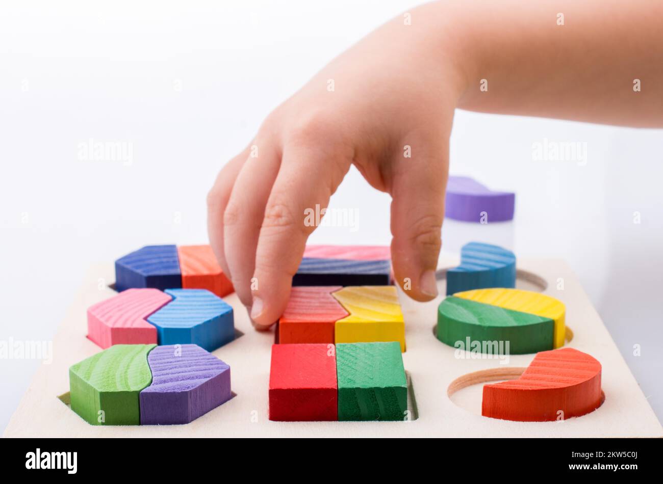 Colorful wooden pieces of a logic puzzle in hand Stock Photo - Alamy