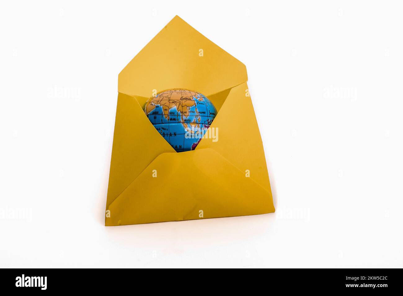 Small earth model in a yellow envelope on a white background Stock ...