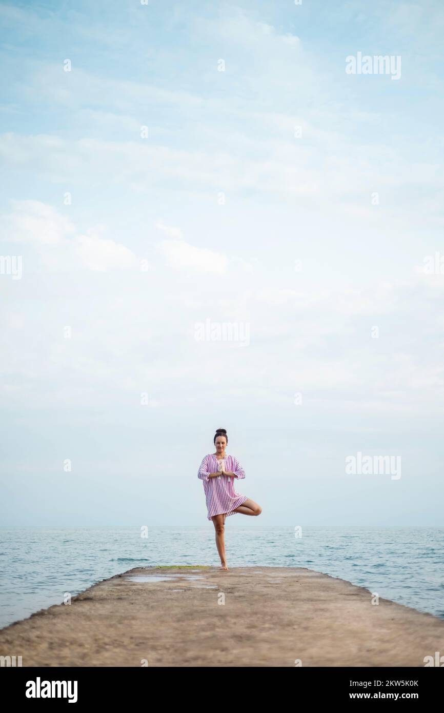 Active female practicing yoga vrikshasana tree pose hands namaste at ...