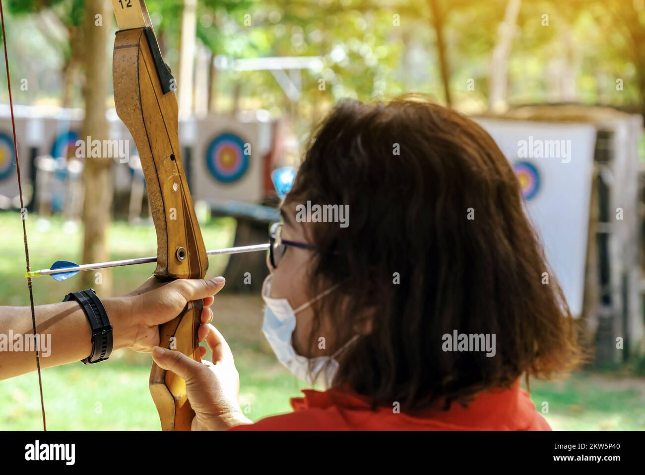 Female teacher teaches student to aim at goal. An archer teaching young ...