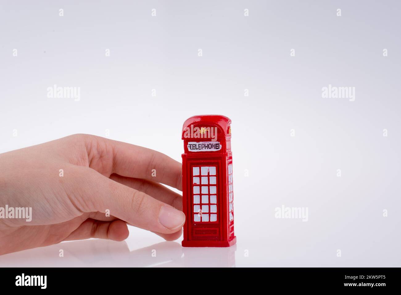 Hand holding a phone booth on a white background Stock Photo - Alamy