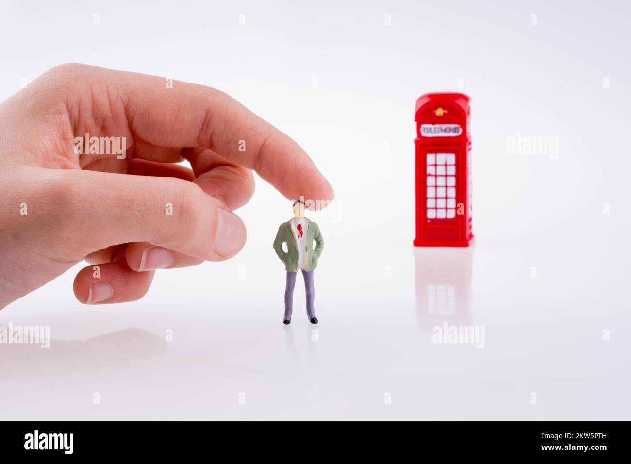 Hand holding a figure near a phone booth on a white background Stock ...