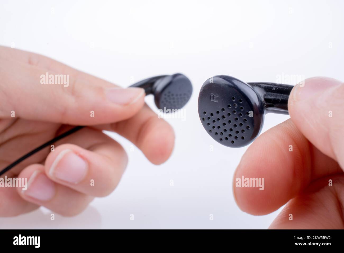 Hand holding a black earphone on a white background Stock Photo - Alamy