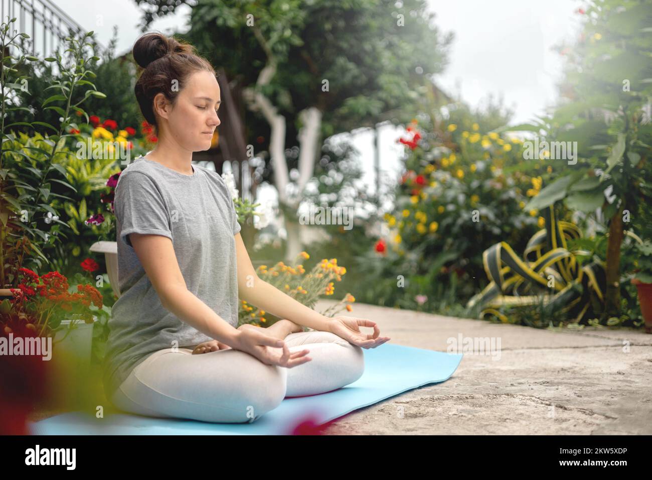 Concentrated woman sitting in lotus position yoga at summer garden park ...
