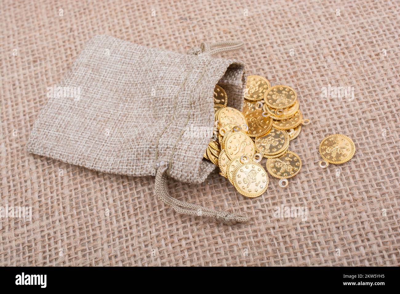 Fake gold coins out of a little sack on canvas Stock Photo - Alamy