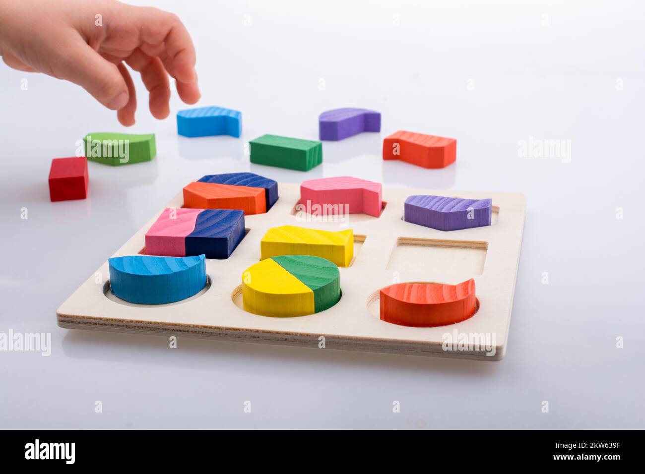 Colorful wooden pieces of a logic puzzle in hand Stock Photo - Alamy