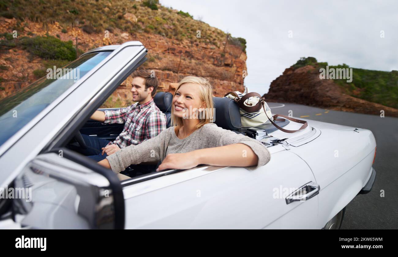 Cruising with the top down. a young attractive couple going for a drive ...