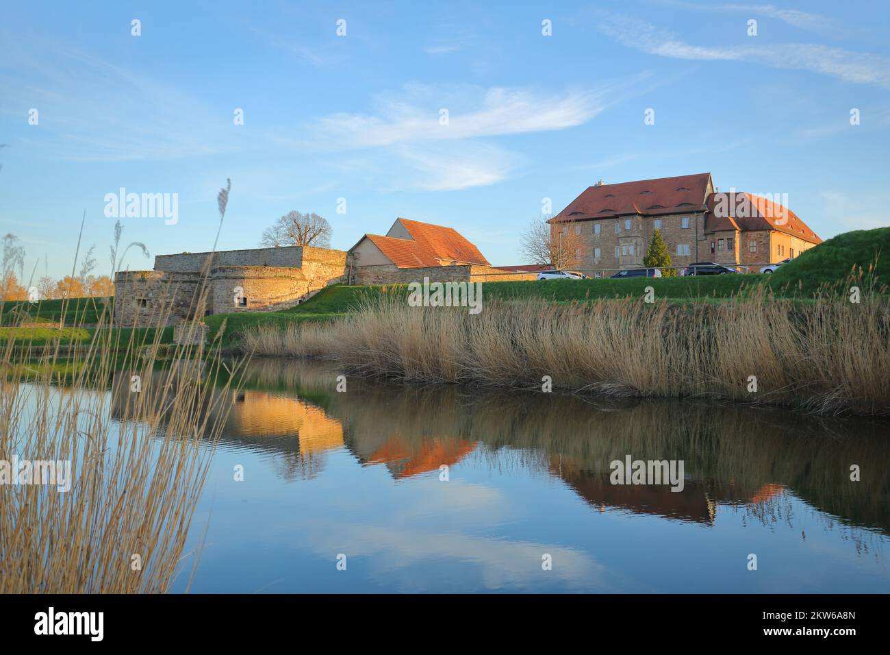Renaissance moated castle with reflection in the pond and reed grass ...