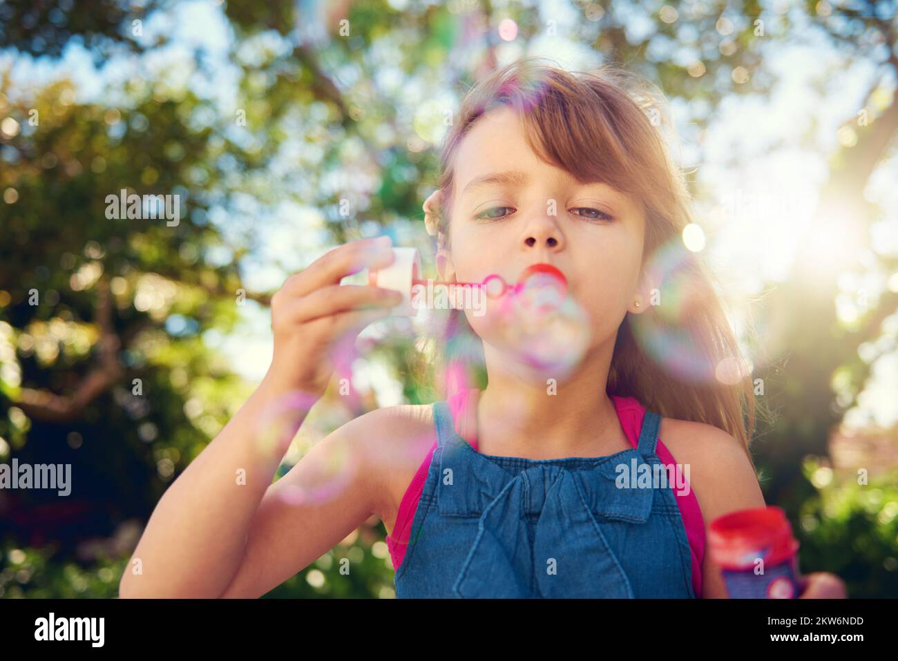 Childhood lasts all through life. a cute young girl blowing bubbles ...
