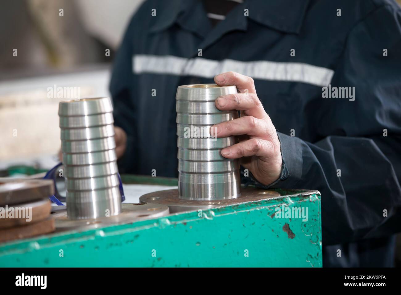 Turning shop or production. Worker's hands hold a metal product ...