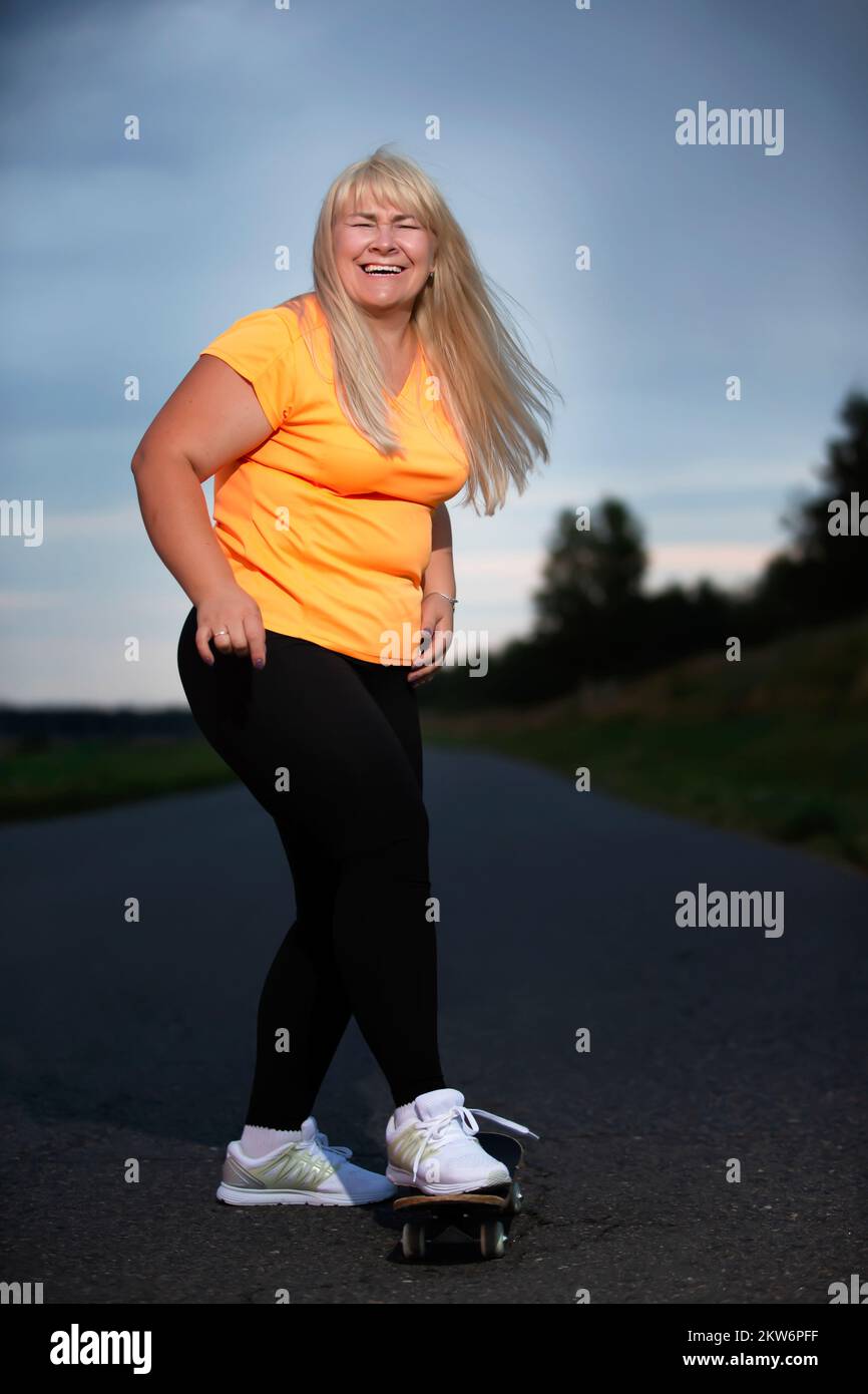 Chubby middle-aged European woman, overweight, in a tracksuit, learns ...