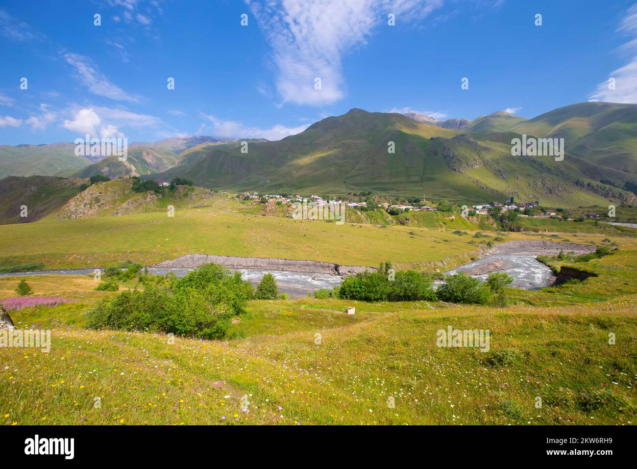 A beautiful mountain landscape with a small meandering river and a blue ...