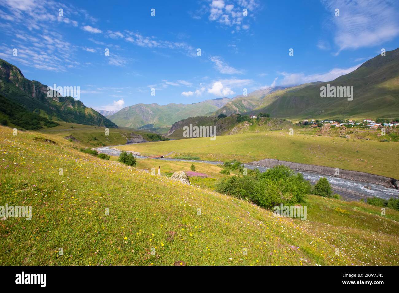 A beautiful mountain landscape with a small meandering river and a blue ...