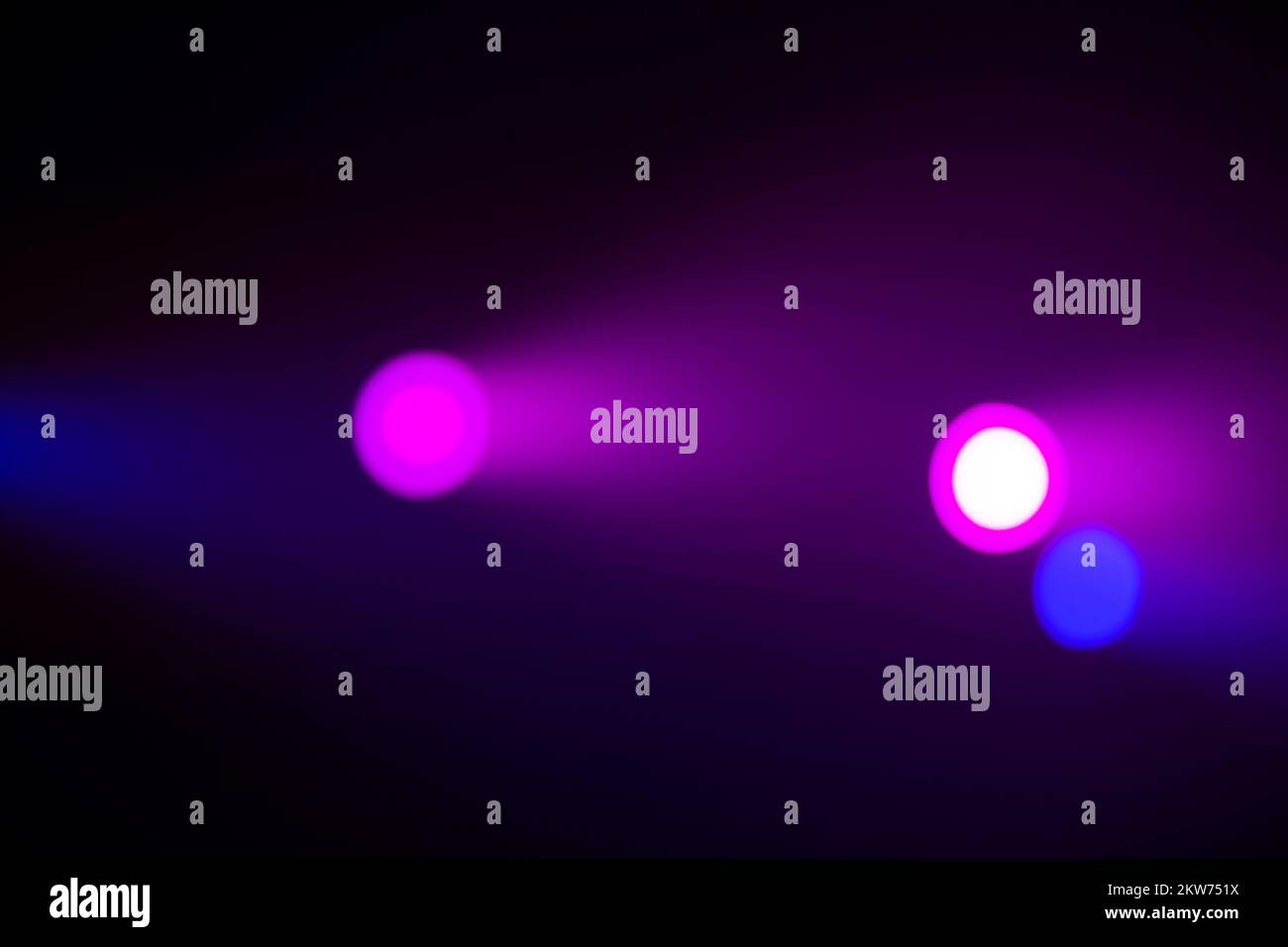 Pink beams of light from stage spotlights on a dark blue background ...
