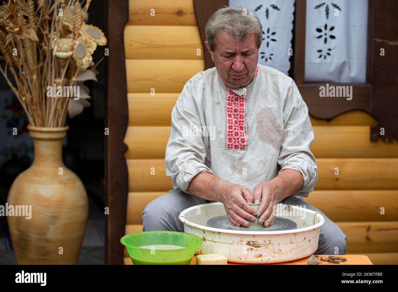 An elderly Slavic man in a Belarusian linen embroidered shirt scul ...
