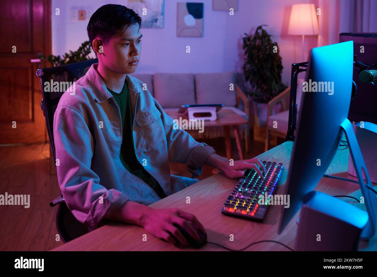 Serious teenage boy working on computer in neon bedroom Stock Photo - Alamy
