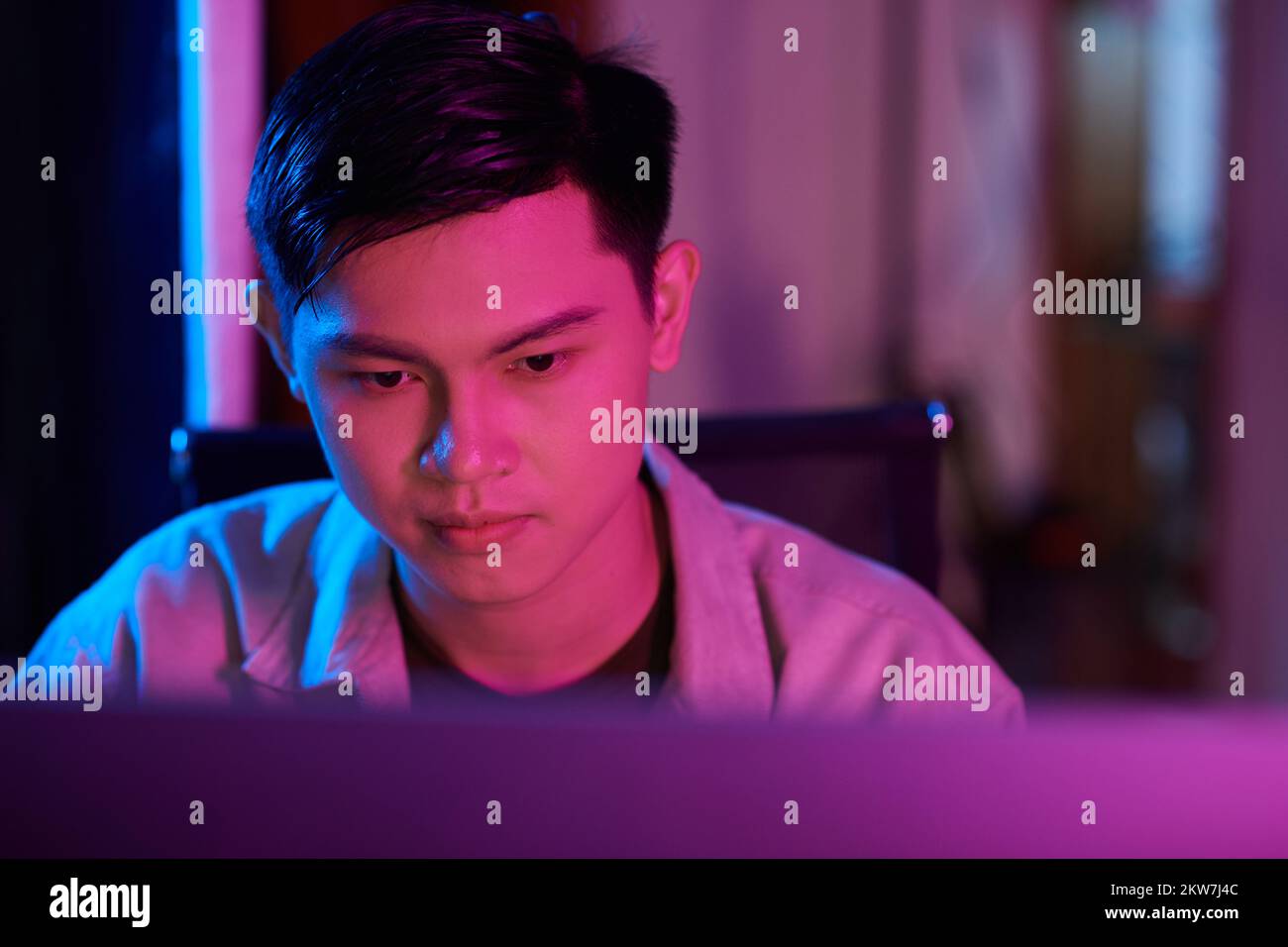 Serious teenage gamer playing on computer in neon bedroom Stock Photo ...