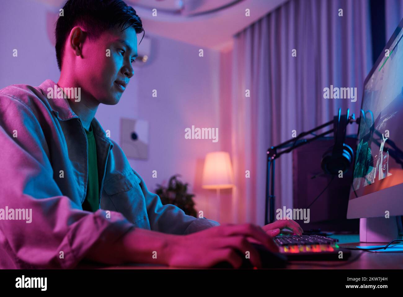 Teenage boy playing video game on computer in his neon bedroom Stock ...