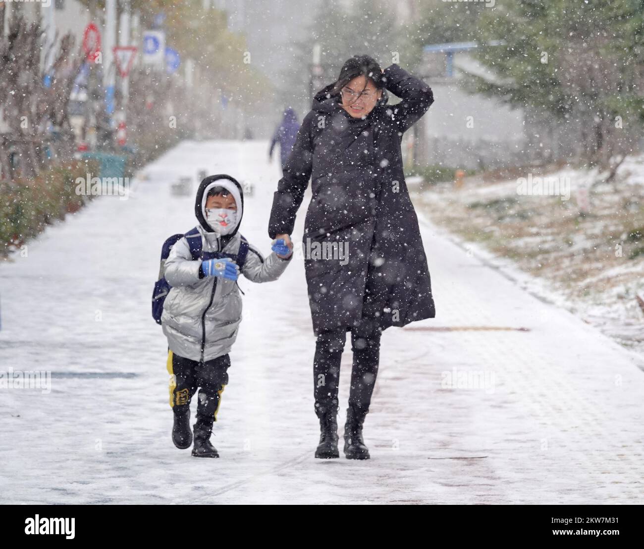 YANTAI, CHINA - NOVEMBER 17, 2022 - People brave snow on a street in ...