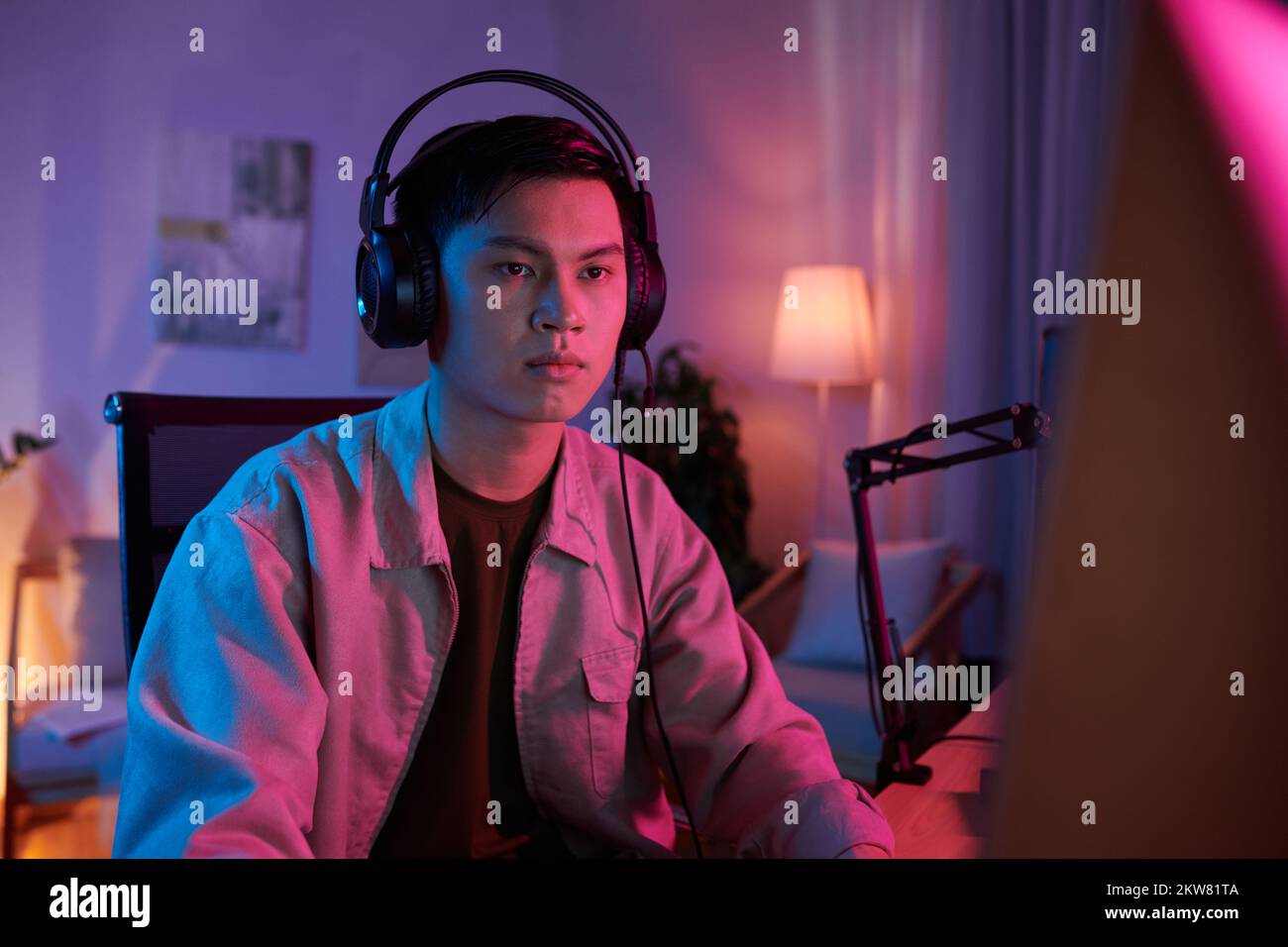 Serious videogamer wearing headphones when playing game on computer ...