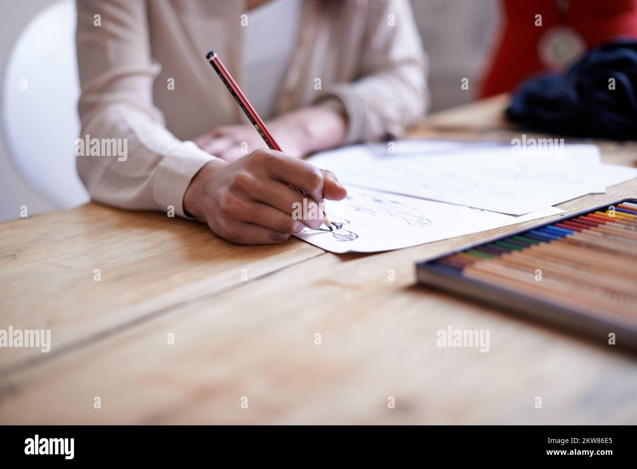 Coming up with new style trends. A fashion designer drawing sketches in ...