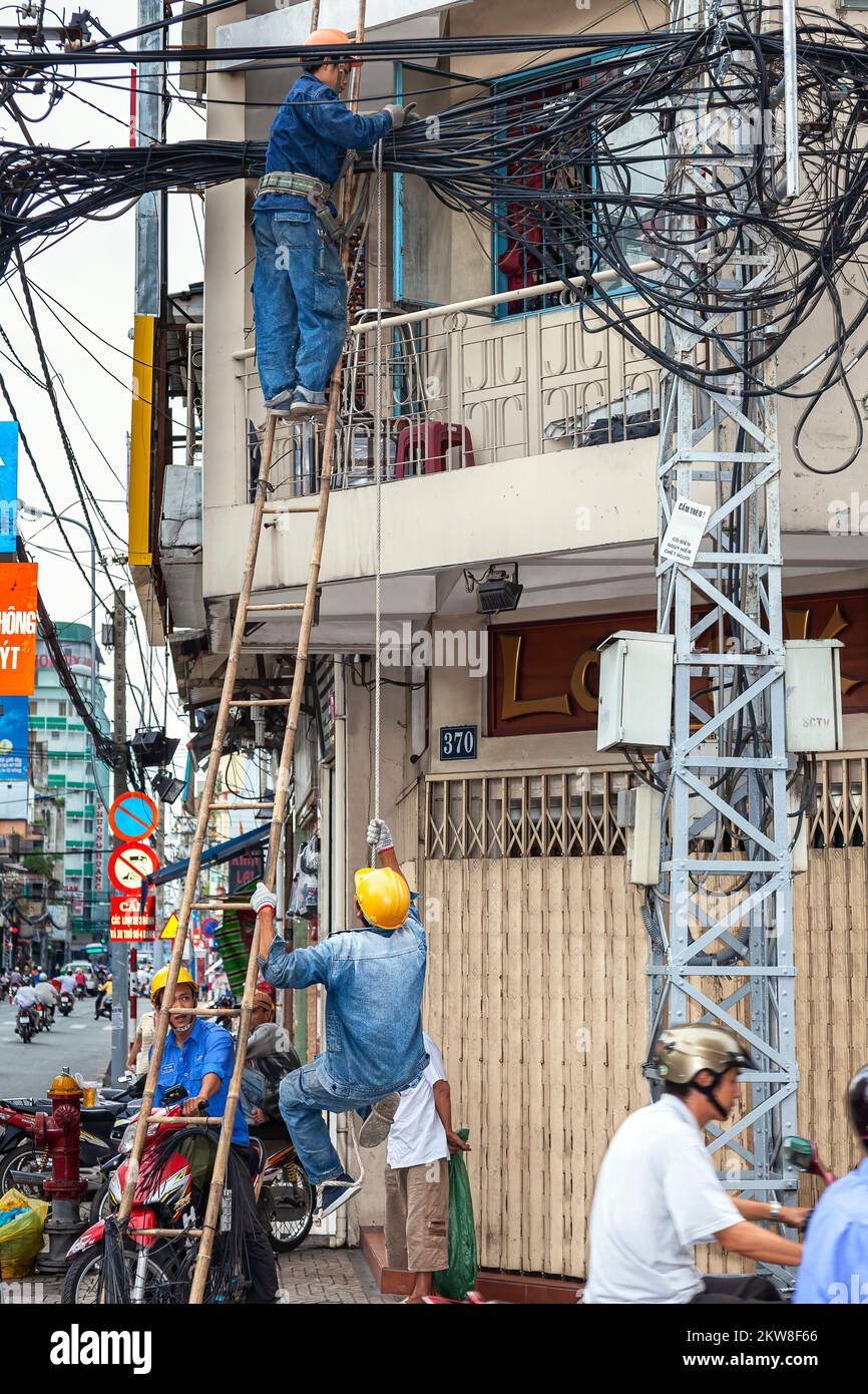 Vietnamese workers using ropes and ladders repairing cables, Ho Chi ...