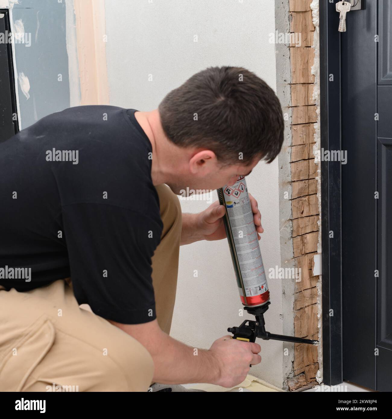 a man uses a spray gun with his hand and fills the gap with ...