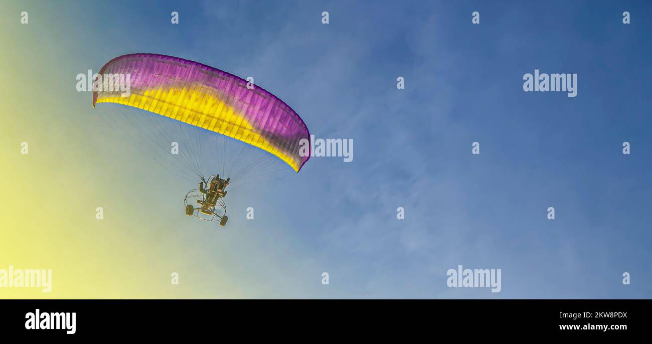 The paraglider with a motor flies in the blue sky Stock Photo - Alamy