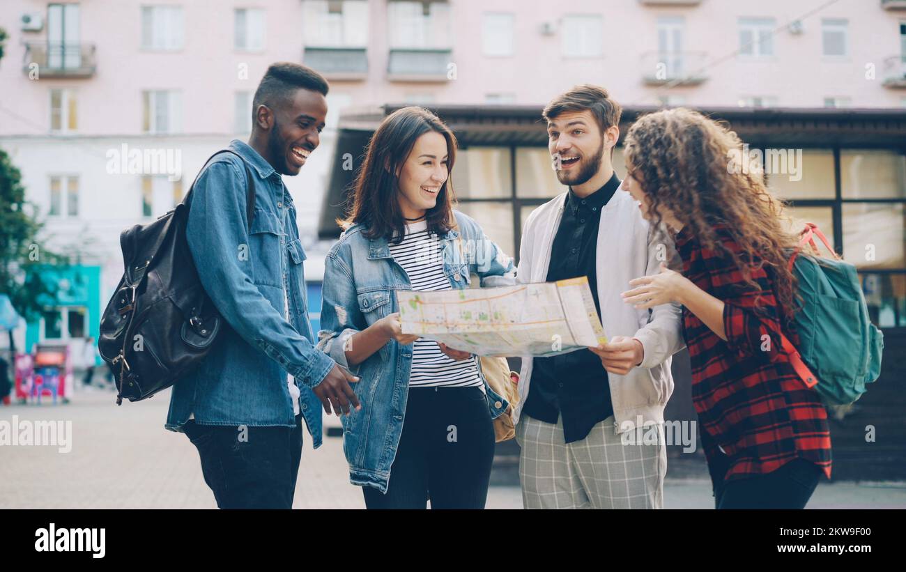 Multiracial group of tourists is looking at paper map standing in the ...