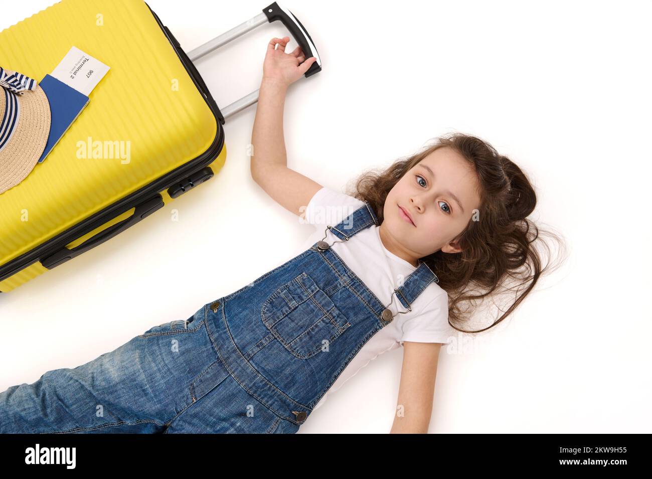 Overhead view happy child with yellow suitcase, waiting to board the ...