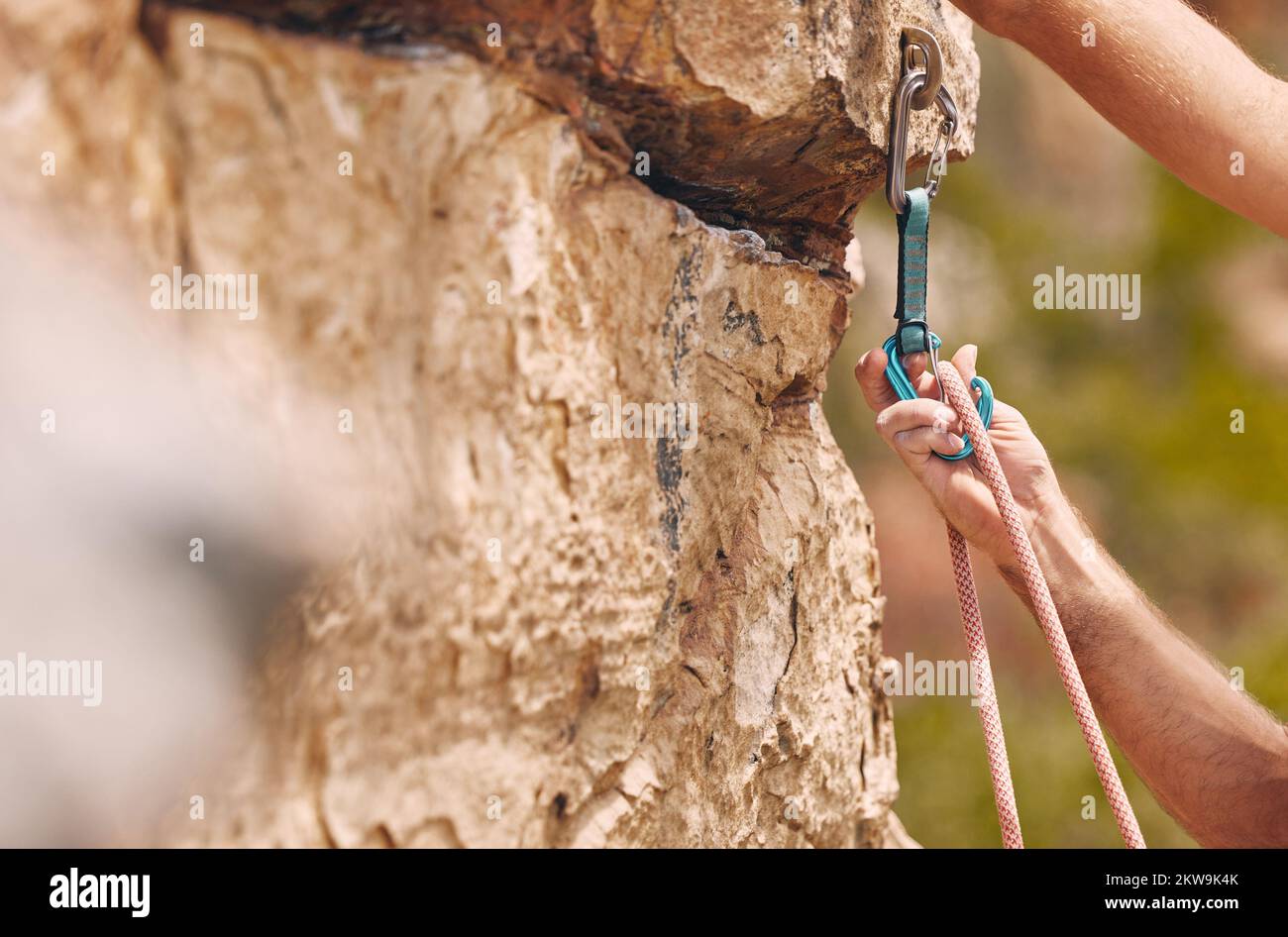 Man hand with carabiner while mountain or rock climbing. male checking his safety and security ...